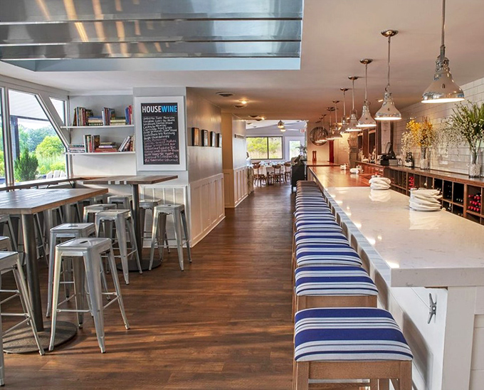 The sleek bar area invites lingering conversations over oysters and wine, where coastal casual meets sophisticated sipping.