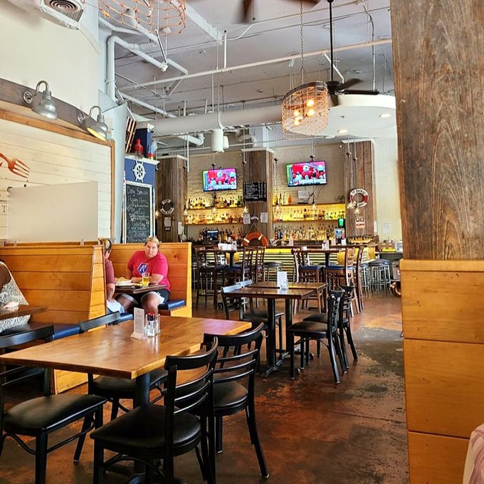 Industrial-chic meets coastal comfort in a space where exposed ductwork and wooden booths create the perfect backdrop for seafood indulgence.