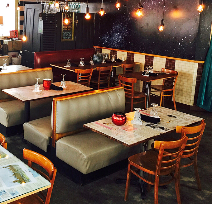 Edison bulbs illuminate booth seating against a cosmic backdrop &ndash; dining under the stars without worrying about Indiana weather.