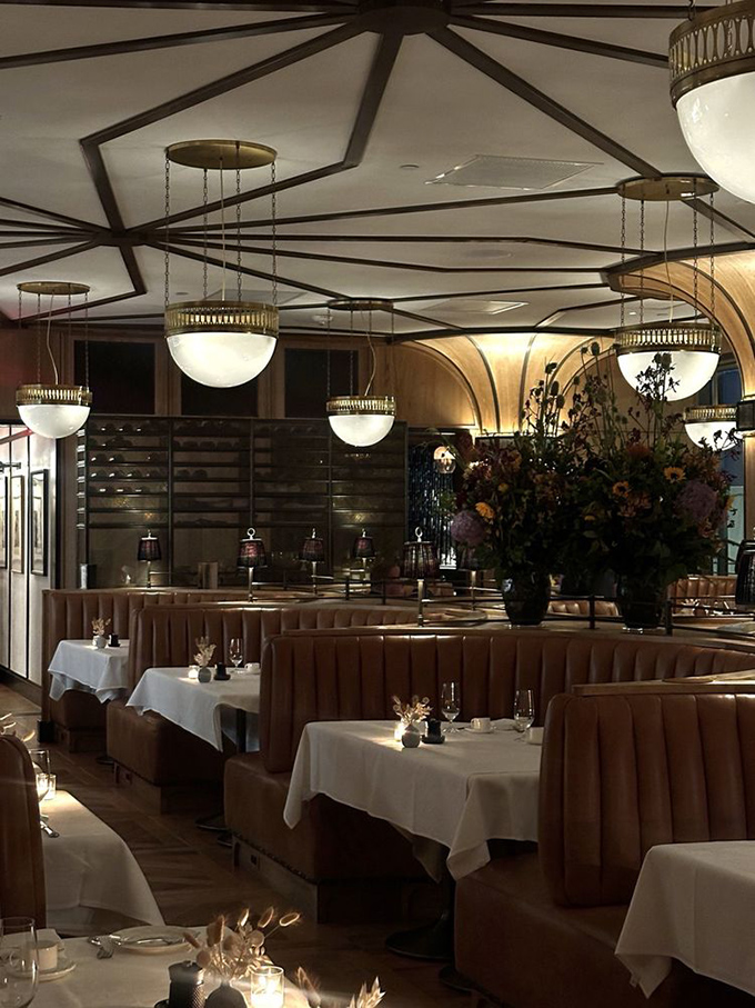 Dramatic lighting transforms dinner into theater, with globe pendants casting a glow that makes everyone look like they're in a Nancy Meyers film.