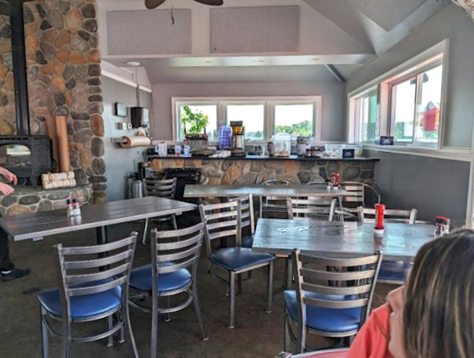 The stone fireplace anchors this dining space with casual elegance. Those blue chairs aren't just seating&mdash;they're front-row tickets to a seafood symphony.