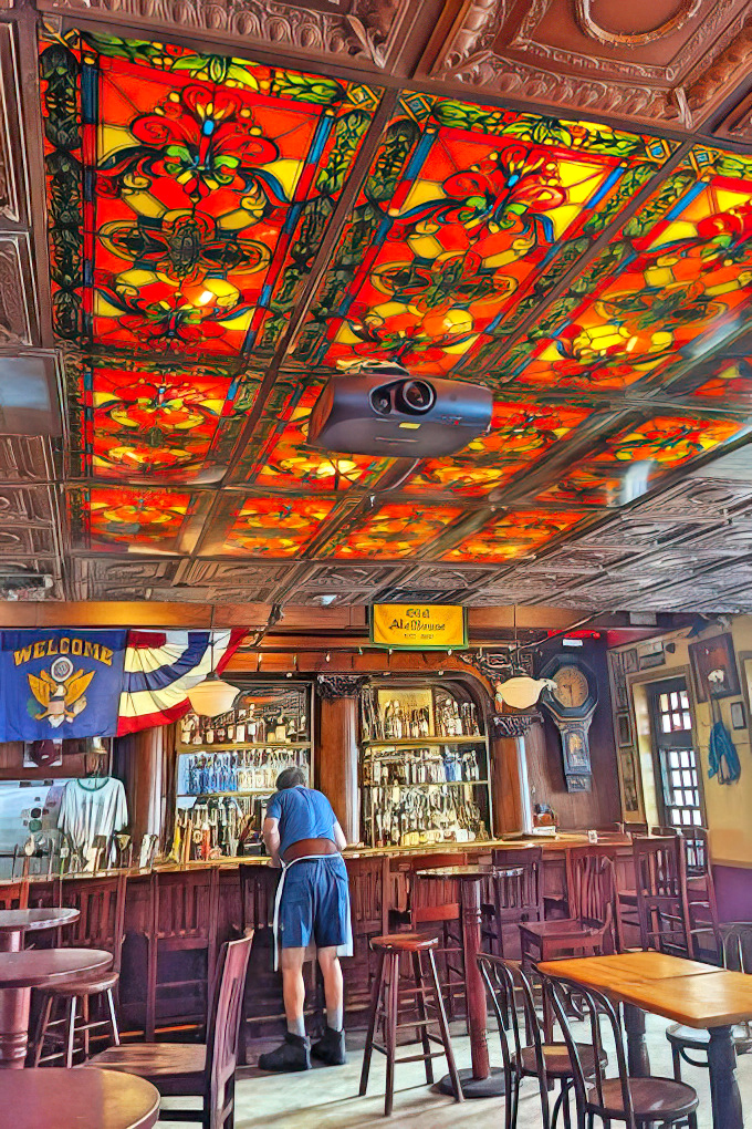 Stained glass ceiling panels transform ordinary bar light into a kaleidoscope of warmth, proving even tavern ceilings can aspire to cathedral-like beauty.