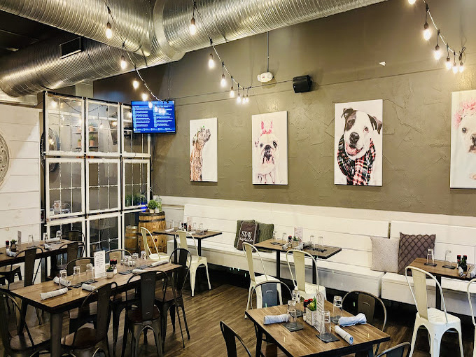 Modern industrial meets cozy neighborhood pub, where dog portraits watch over diners like benevolent four-legged guardians of good taste.