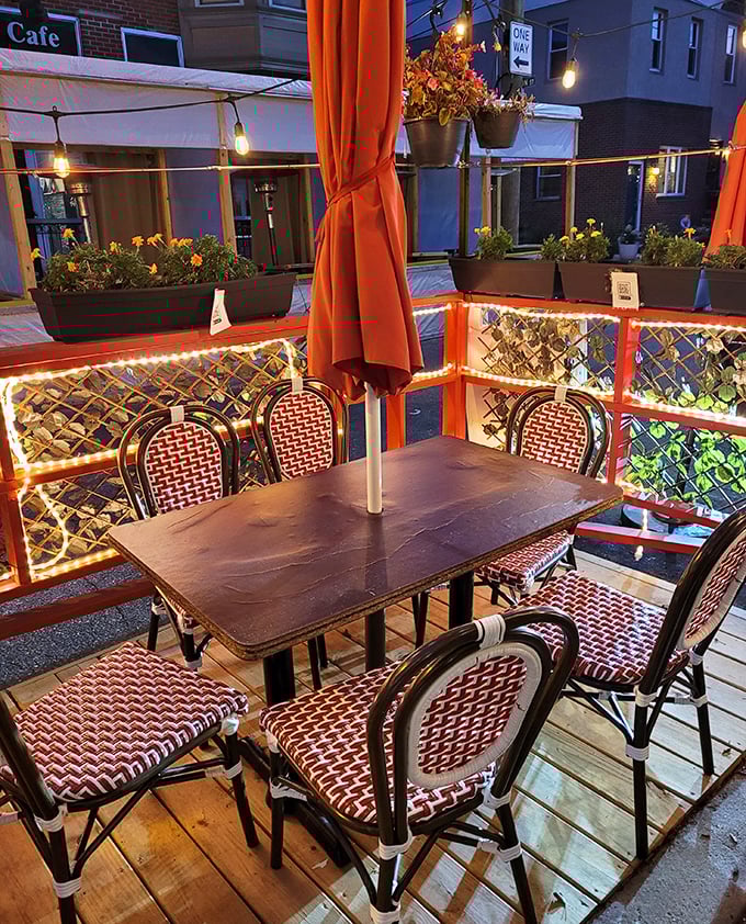 The outdoor seating area glows with string lights and red umbrellas, creating a romantic Parisian-meets-Philadelphia atmosphere perfect for summer evenings.