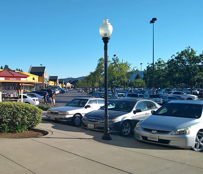 A sea of vehicles with empty trunks, soon to be filled with treasures. The parking lot: where shopping journeys begin and credit cards tremble.