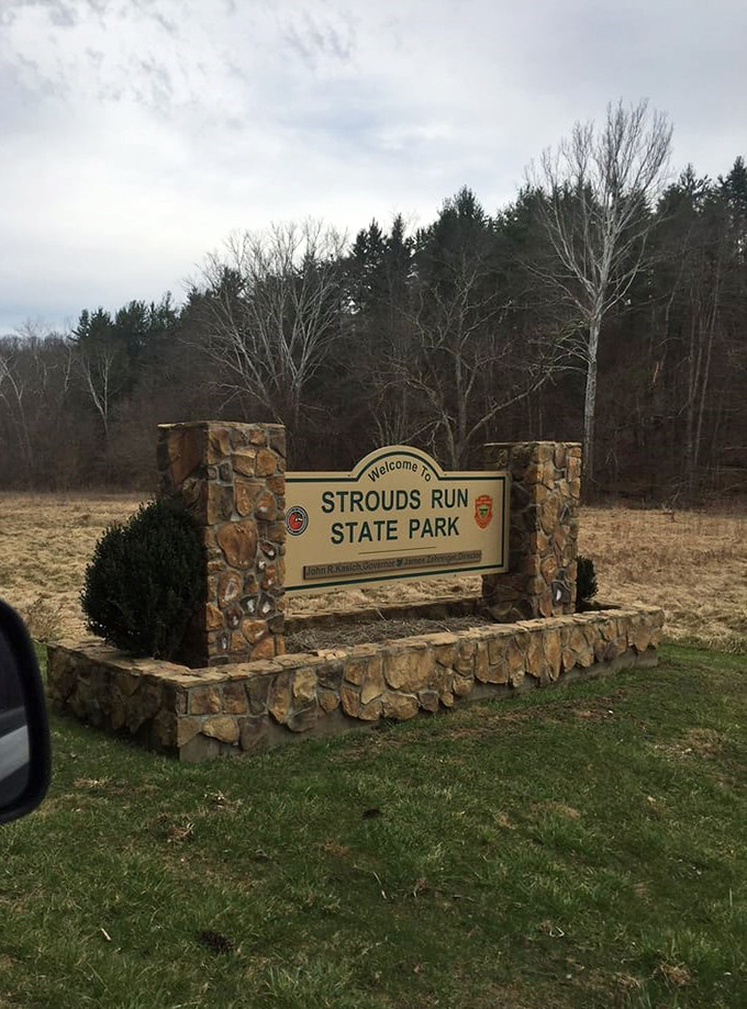 The stone entrance sign stands as a rustic gatekeeper between everyday life and the natural sanctuary that awaits beyond.