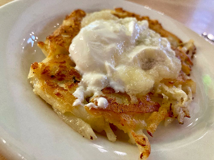 The humble potato pancake, elevated to art form – crispy edges giving way to tender centers, crowned with a dollop of sour cream.