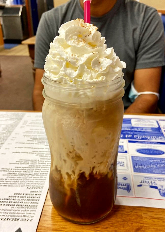 A mountain of whipped cream atop what appears to be a mason jar of caffeinated bliss – because sometimes coffee needs to dress up and go to the ball.