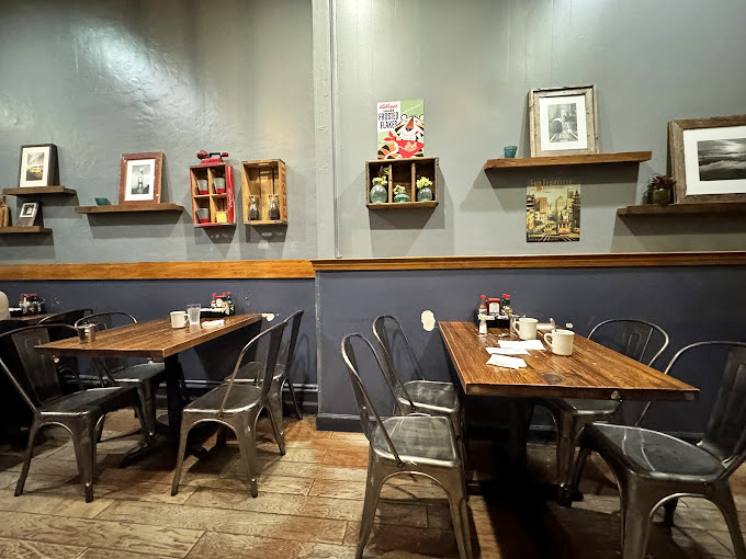 Metal chairs and wooden tables create an industrial-cozy vibe. The wall shelves display San Francisco mementos that feel like they're from someone's actual home. 