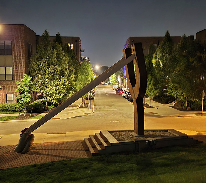 Nighttime transforms the urban landscape around The Slingshot, with street lights illuminating the path to this after-dark destination.