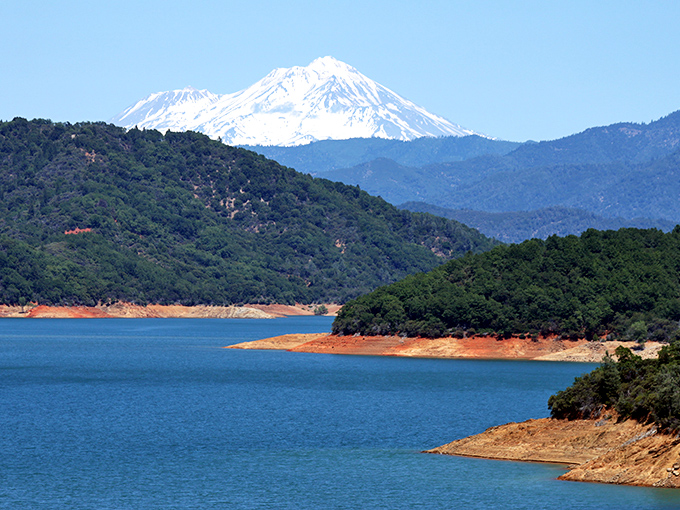 Shasta Lake's crystal waters reflect the surrounding mountains. Nature's mirror with fishing opportunities included at no extra charge!