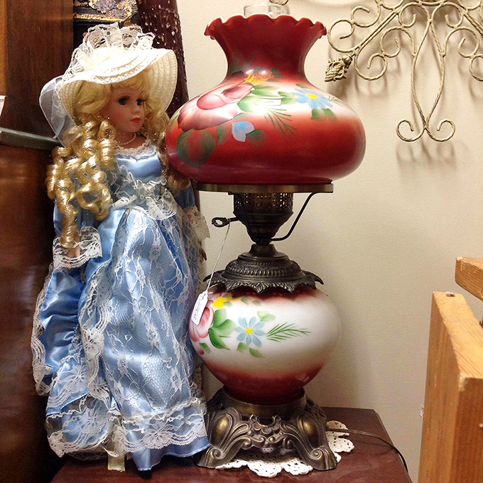 A vintage lamp with its hand-painted floral globe stands sentinel beside a porcelain doll&mdash;together they've witnessed decades of family conversations.