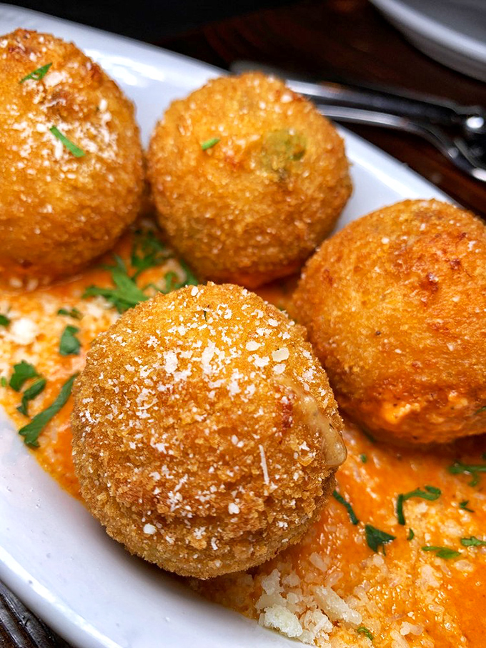 Arancini that could make a Sicilian weep with joy. These golden orbs of risotto perfection sit in a pool of sauce that demands to be scooped up with bread.