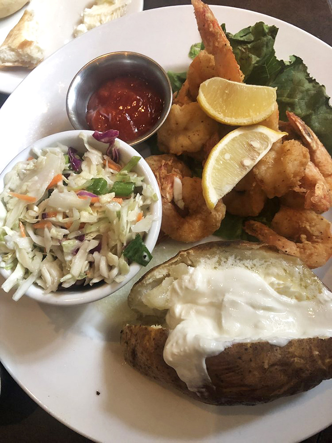 The holy trinity of Southern comfort: Crispy fried shrimp, creamy coleslaw, and a baked potato dressed in its Sunday best.