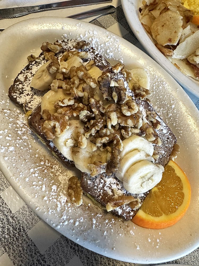 French toast that makes regular bread feel inadequate. Banana, nuts, and powdered sugar create a breakfast that's basically acceptable cake.
