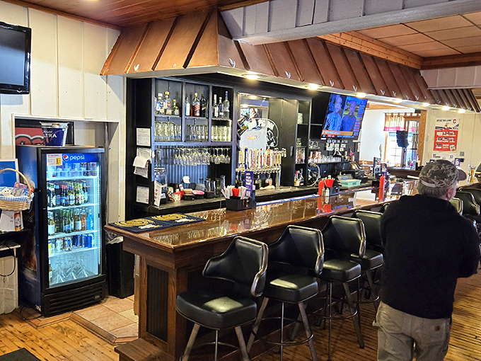 A bar that understands its purpose: cold drinks, good company, and a front-row seat to watch culinary magic happen just beyond those swinging doors.