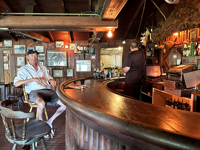The curved wooden bar has likely heard more secrets than a priest's confessional, with a patron enjoying a quiet moment of reflection.
