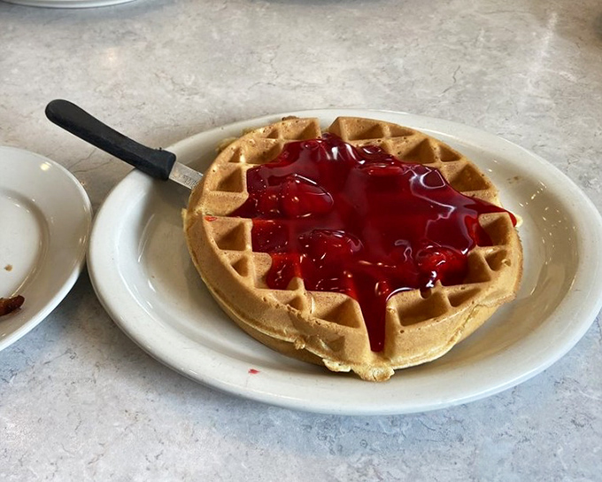 A Belgian waffle wearing a ruby crown of strawberry topping. The perfect balance of crisp exterior and fluffy interior—architecture you can eat.