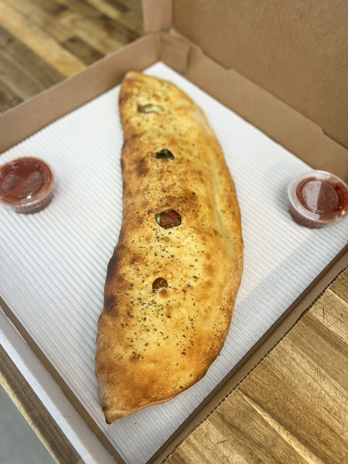 The calzone—pizza's mysterious, folded cousin. Those marinara dipping cups aren't accessories—they're essential companions on this half-moon journey.