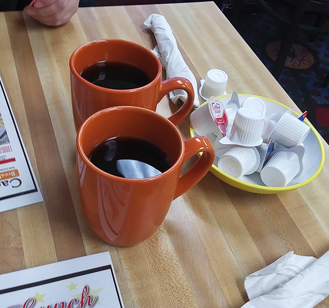 Orange mugs filled with liquid motivation - because every great breakfast adventure begins with proper coffee preparation.