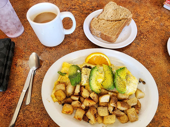 Fresh fruit and whole wheat toast play supporting roles to the real star&mdash;a vibrant omelet adorned with avocado slices like emerald medals of honor.