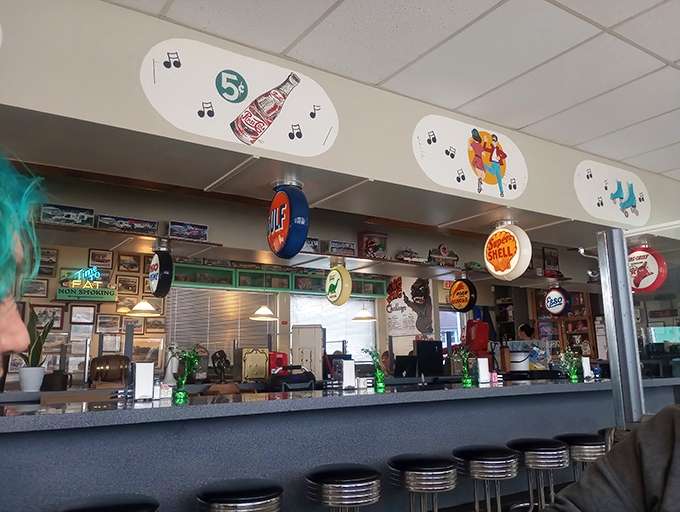 The counter view reveals a museum of Americana, where Coca-Cola meets Sohio Supreme, and musical notes dance above classic car illustrations.