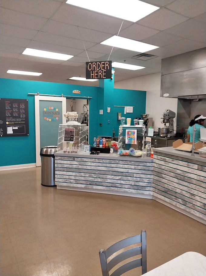 The heart of donut operations, where friendly staff transform simple ingredients into rings of joy behind that distinctive teal wall. 