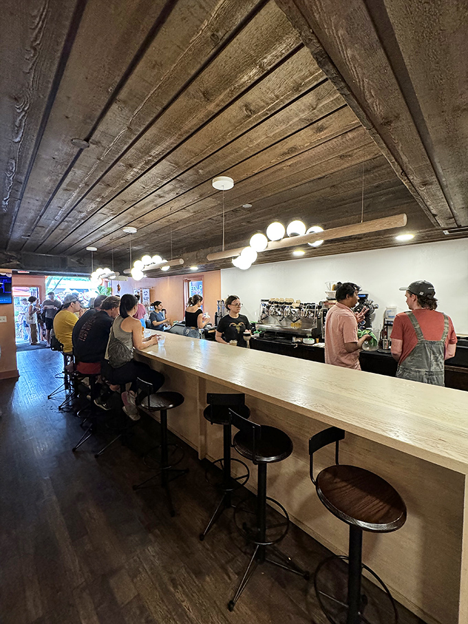 A sleek wooden counter where coffee magic happens and strangers become temporary neighbors united by good taste.