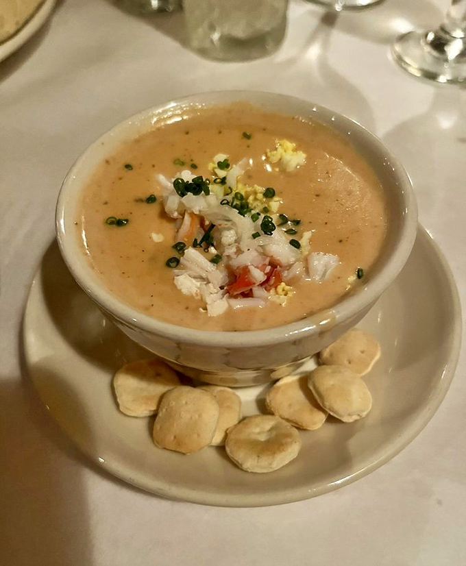 This crab bisque isn't just soup—it's a velvety ocean hug in a bowl, garnished with fresh crab and served with crackers for necessary dunking.