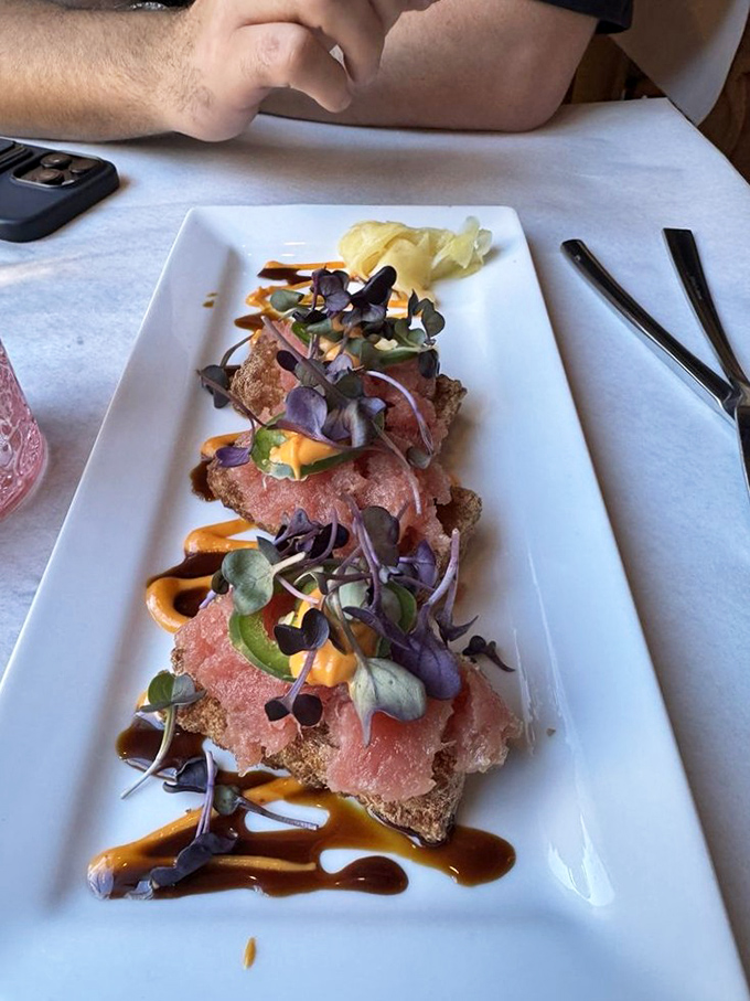 Tuna tartare elevated with microgreens and artistic sauce drizzles&mdash;proof that some of the best food never meets a flame.