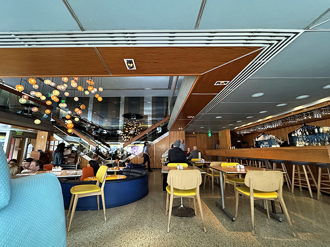 The multi-level dining space features dramatic lighting, curved booths, and a color palette that feels like the 1960s jetted into the future.