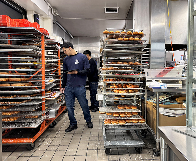 Behind-the-scenes donut magic. These racks hold tomorrow's happiness, with dedicated staff ensuring quality control one tray at a time.