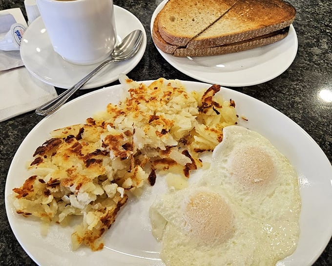 The breakfast trinity: perfectly cooked eggs, golden home fries, and toast standing by for yolk-sopping duty. Morning salvation on a plate.