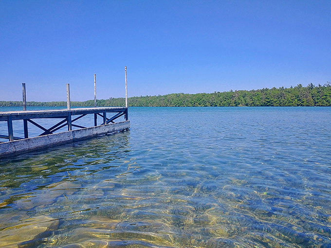 The dock at Europe Lake offers crystal-clear waters so pristine you can count pebbles at surprising depths.