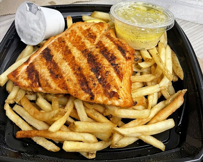 Grilled salmon that flakes with just a glance, surrounded by fries that somehow remain the perfect supporting actors. That grill mark pattern deserves its own design patent.
