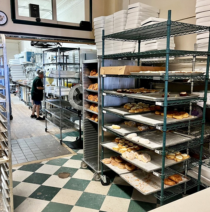 The kitchen's organized chaos reveals the behind-the-scenes artistry where dough becomes dreams on metal racks of possibility.