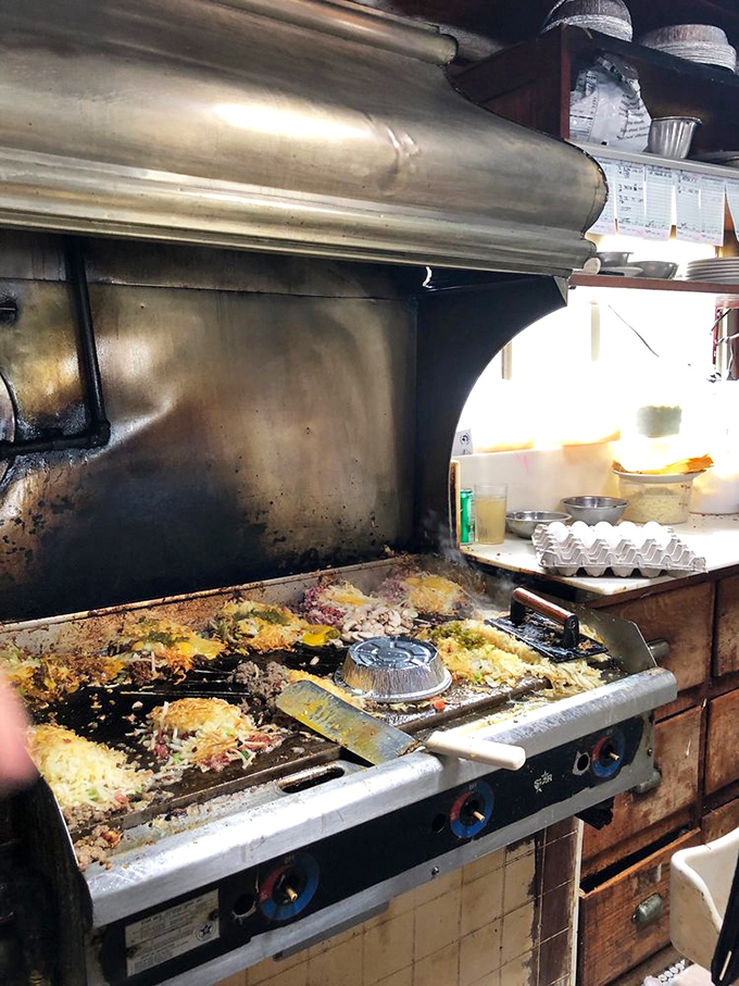 The well-seasoned griddle tells tales of thousands of breakfasts past. This isn't cooking; it's performance art with eggs.