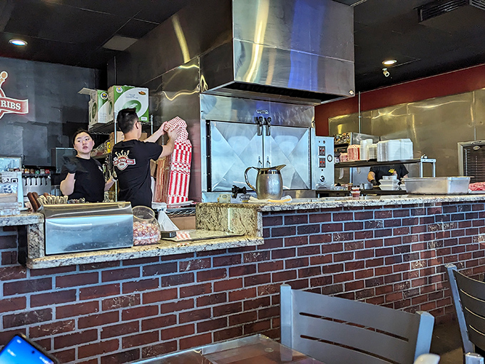 The open kitchen where smoke meets science. Those stainless steel workstations are the laboratories where ordinary cuts become extraordinary meals.