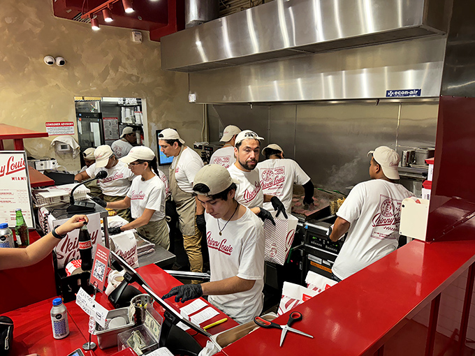 The kitchen crew moves with the choreographed precision of a burger ballet. White uniforms and focused expressions – these folks mean business.