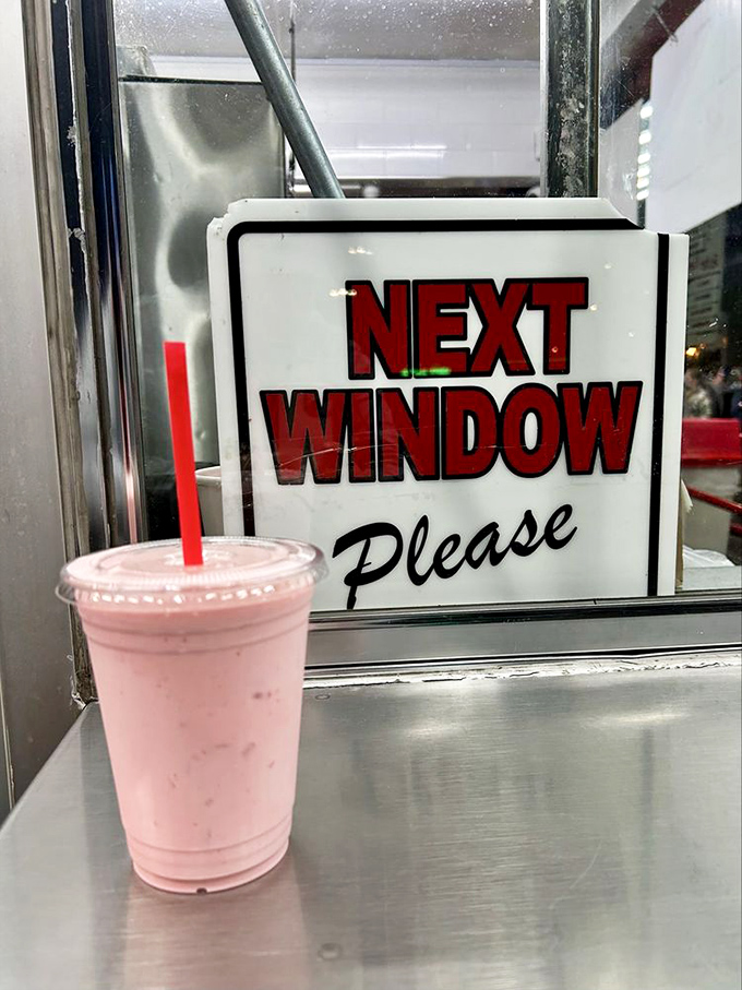 The "Next Window Please" sign paired with a strawberry shake&mdash;a pink reminder that good things come to those who follow the rules.