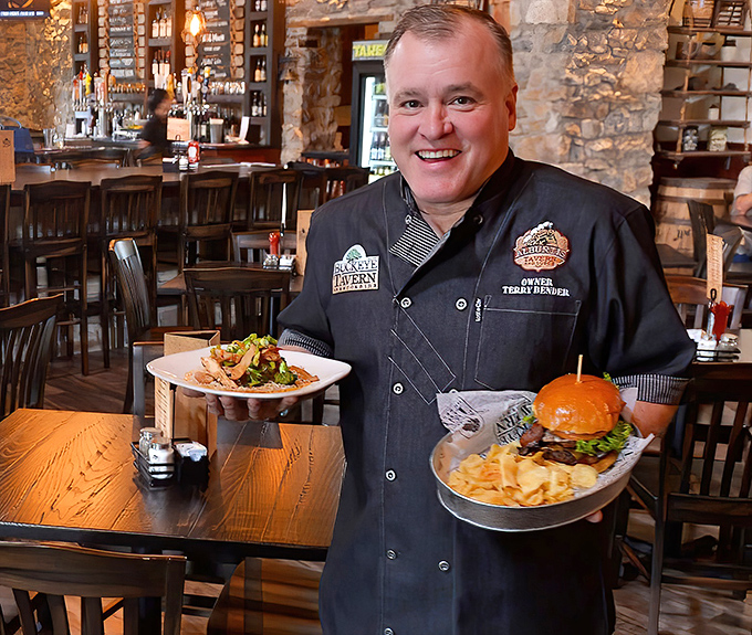 The image shows what appears to be a chef or staff member proudly presenting dishes that represent hours of culinary craftsmanship and generations of tradition.