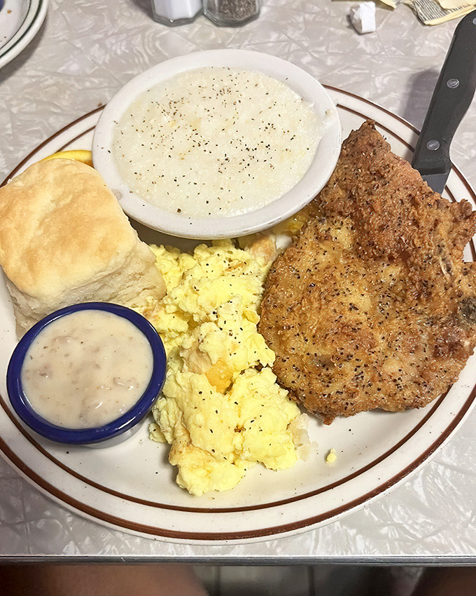 A country breakfast that means business: fluffy biscuit, creamy grits, farm-fresh eggs, and a pork chop that didn't skip gym day.