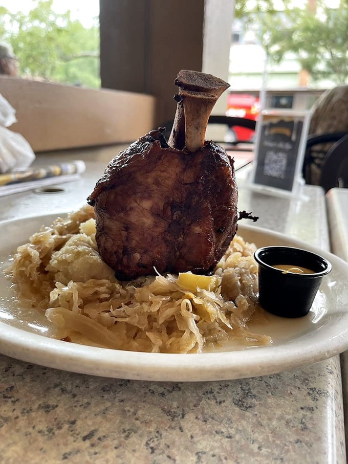 The pork shank arrives standing tall like a meaty monument, tender meat falling from the bone onto a cloud of sauerkraut below.