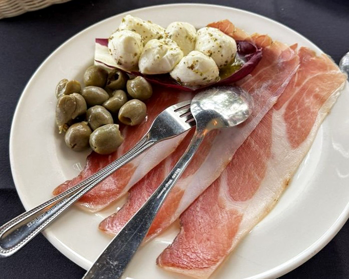 Prosciutto, olives, and fresh mozzarella &ndash; the holy trinity of Italian appetizers presented with elegant simplicity.