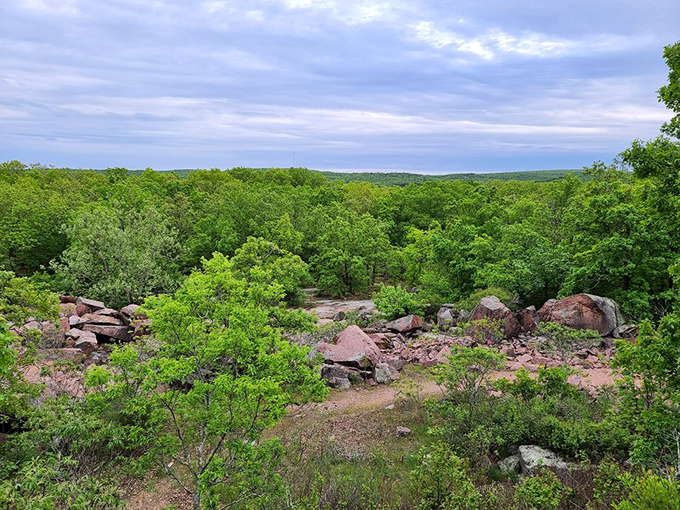 The view stretches for miles across Missouri's rolling landscape. Pink granite boulders punctuate the endless sea of green.