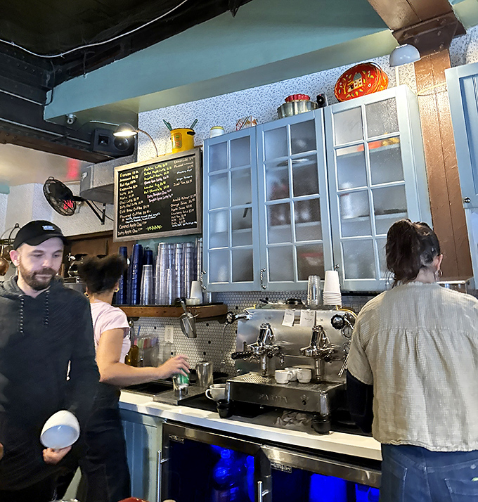 The coffee counter ballet &ndash; where baristas orchestrate morning salvation with practiced hands and the espresso machine hisses approval.