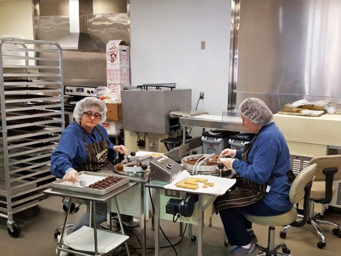 Skilled hands creating chocolate magic with practiced precision. There's something deeply satisfying about watching experts who have perfected their delicious craft.