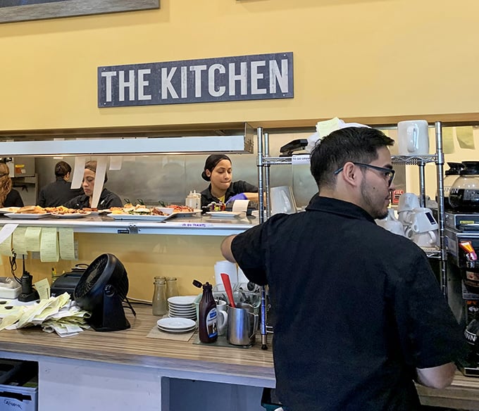 Behind "The Kitchen" sign, breakfast wizards work their morning magic, turning simple ingredients into reasons to get out of bed.