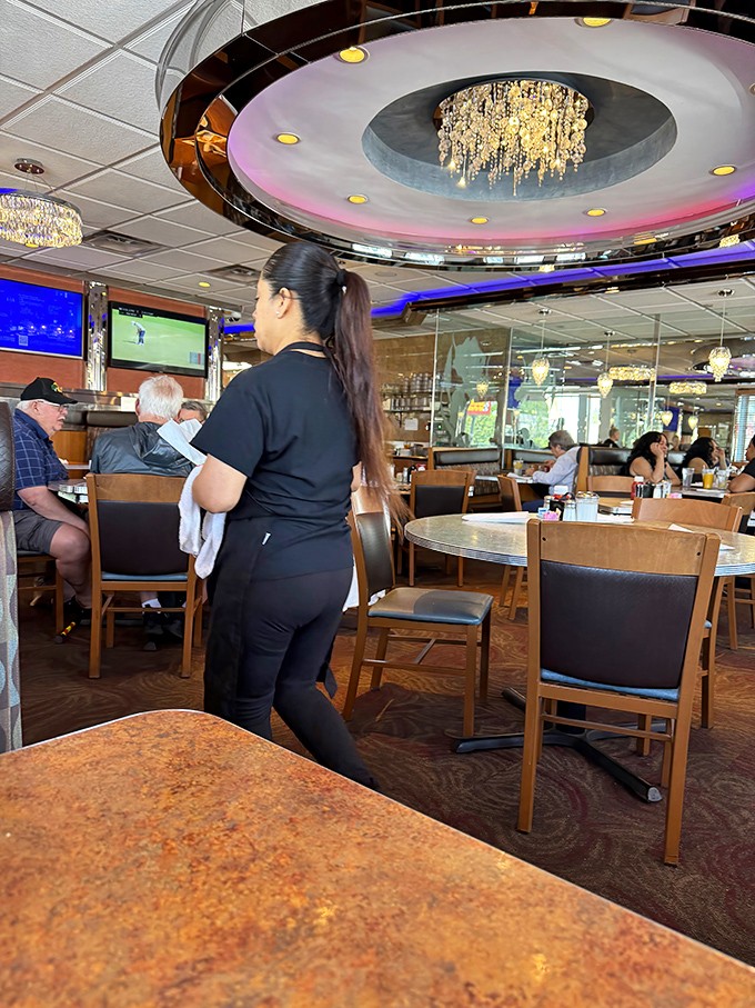 Under the watchful glow of that showstopping chandelier, staff navigate the dining room with the precision of dancers who know every step by heart.