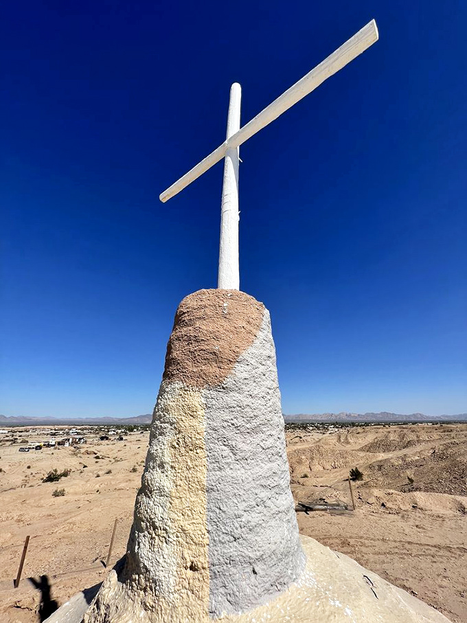 Standing tall against the endless blue sky, the cross marks the highest point of this colorful monument, visible for miles across the flat desert.